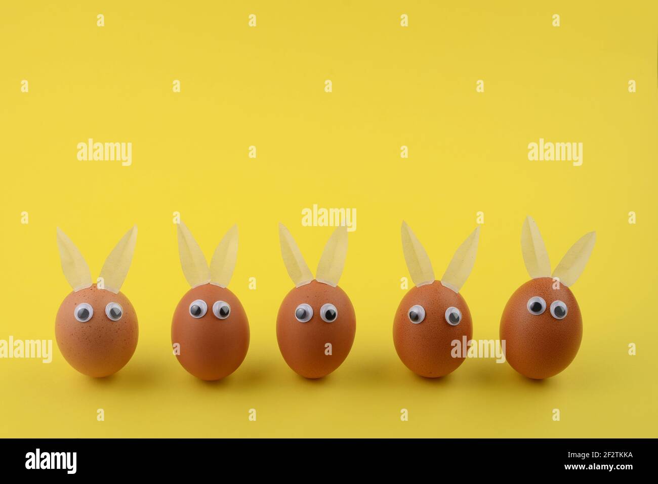 Easter Eggs with eyes and Rabbit ears in a Row on yellow background ...