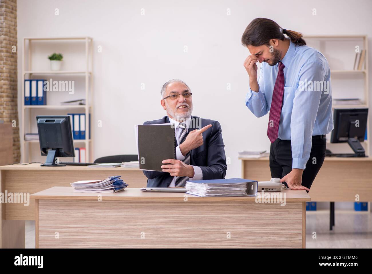 Old boss and young employee working in the office Stock Photo - Alamy