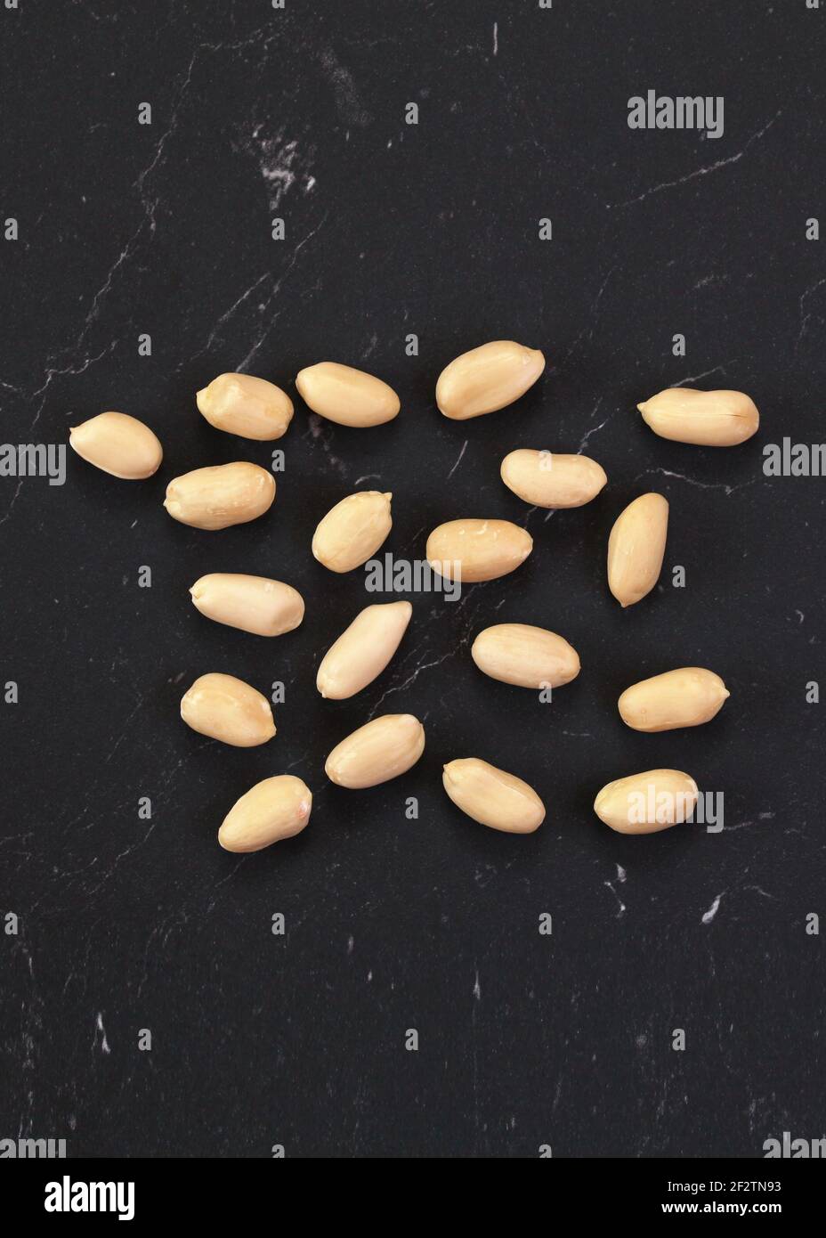 Group of peeled peanuts on black marble like board, closeup detail from ...