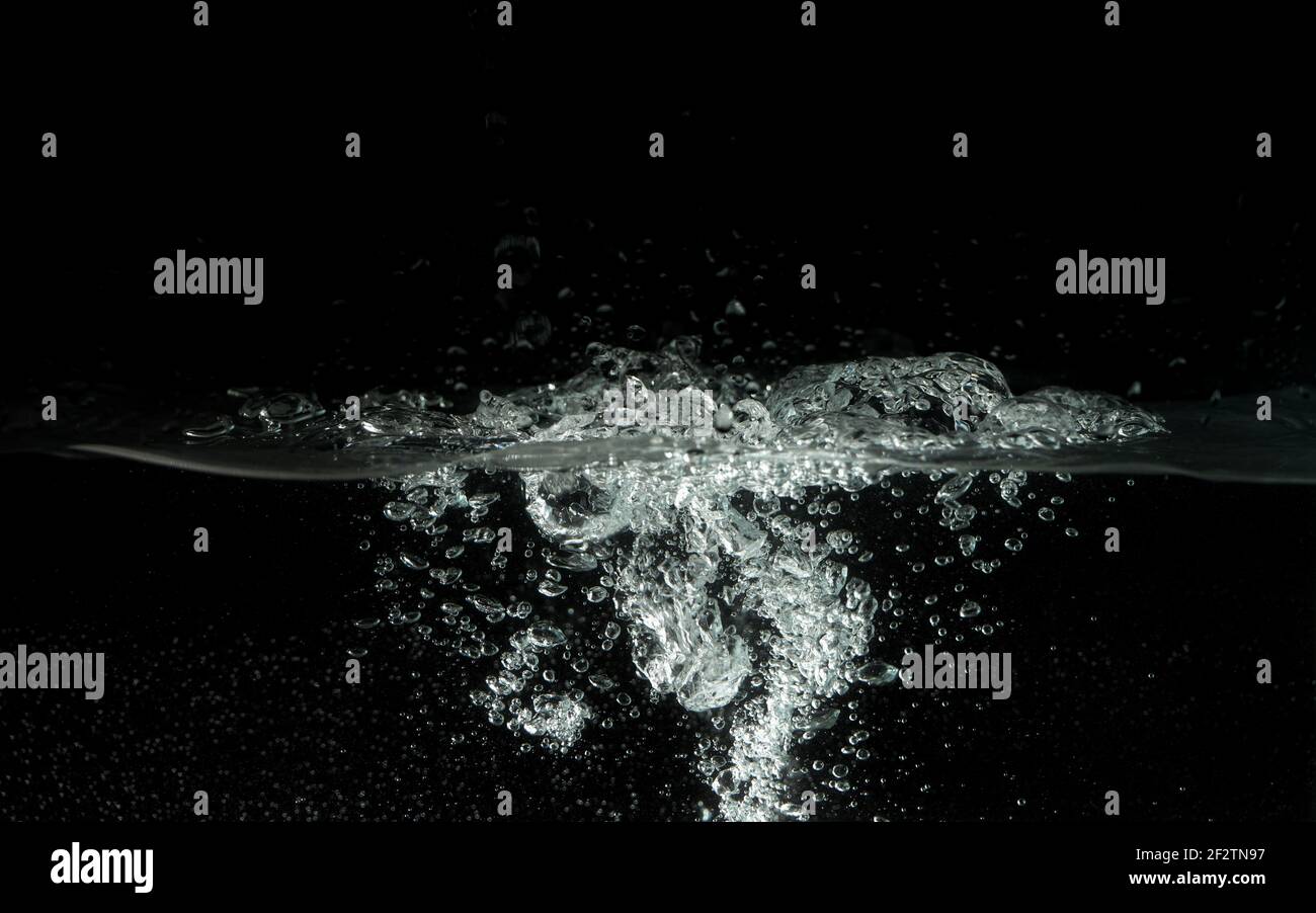 Water splashing as it's poured into aquarium tank, black background ...