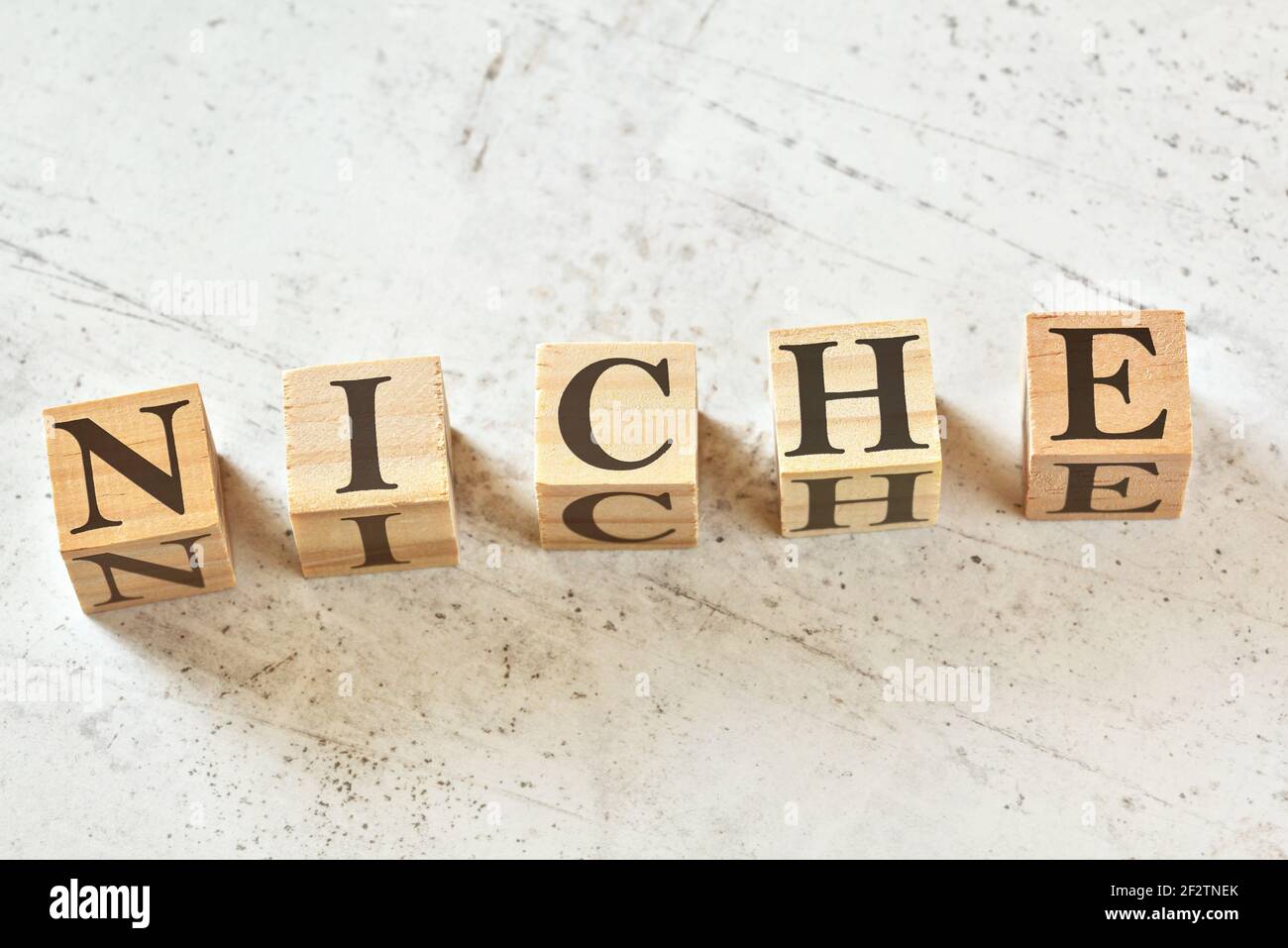 Five wooden cubes with word NICHE on white stone like board, view from ...