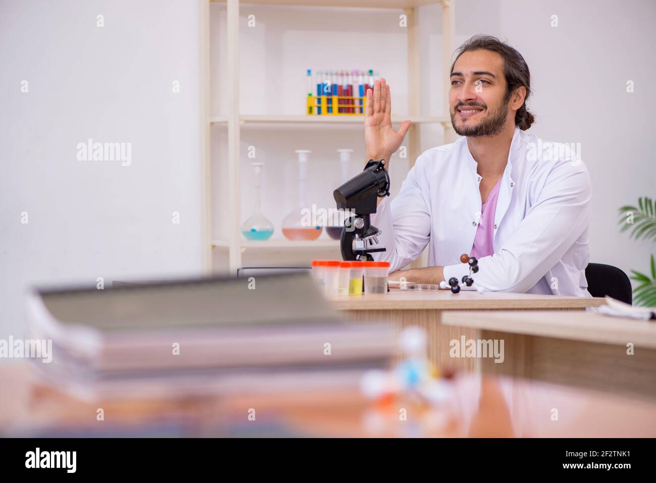 Young chemist sitting at the desk in the classroom Stock Photo - Alamy