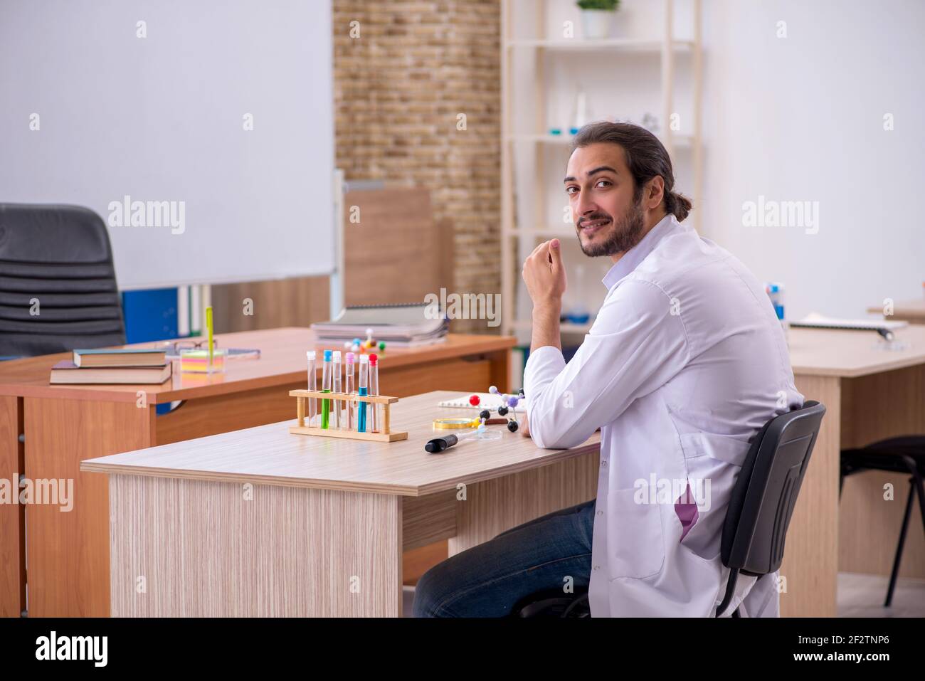 Young chemist sitting at the desk in the classroom Stock Photo - Alamy
