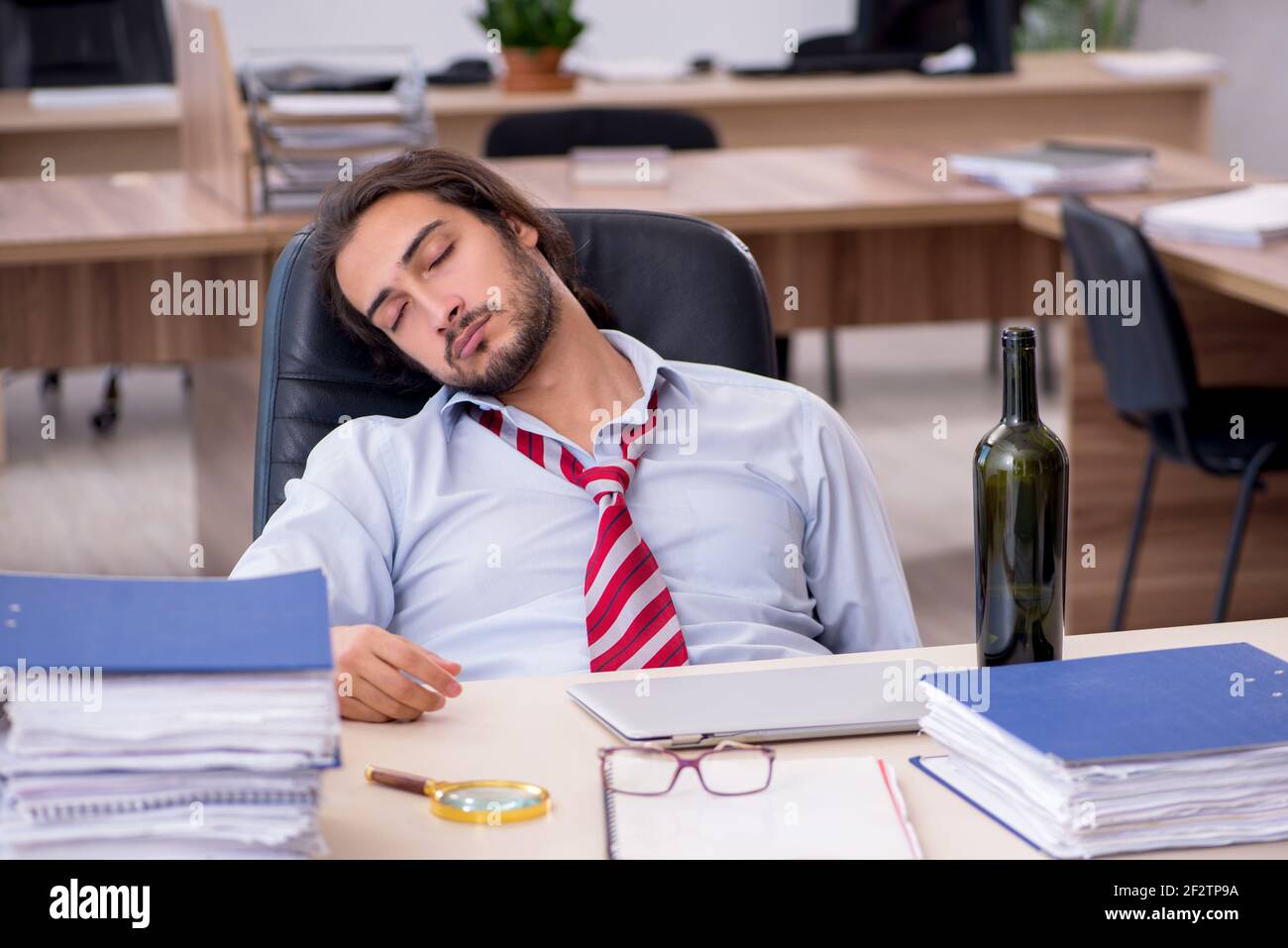 Young male employee drinking alcohol at workplace Stock Photo - Alamy