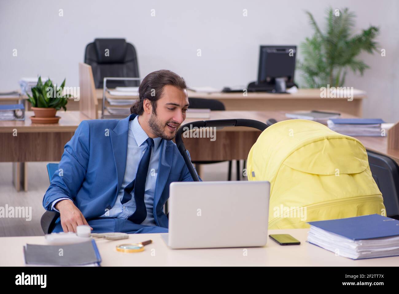 Young male employee looking after new born in the office Stock Photo ...