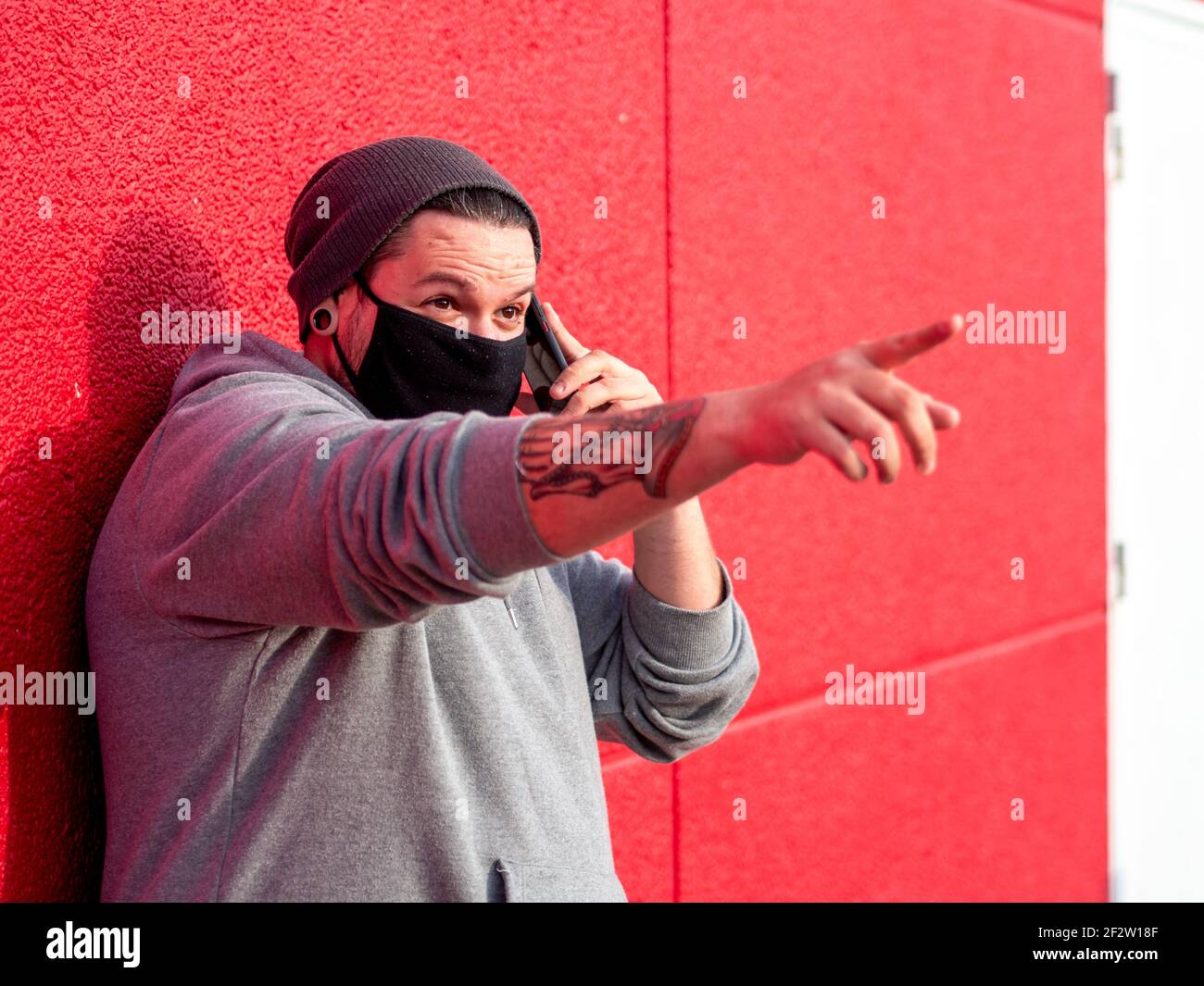 A Spanish Caucasian man standing in front of a red wall, wearing a ...