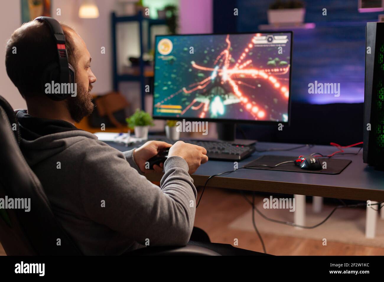 Concentrated gamer playing virtual game on powerful computer at home ...