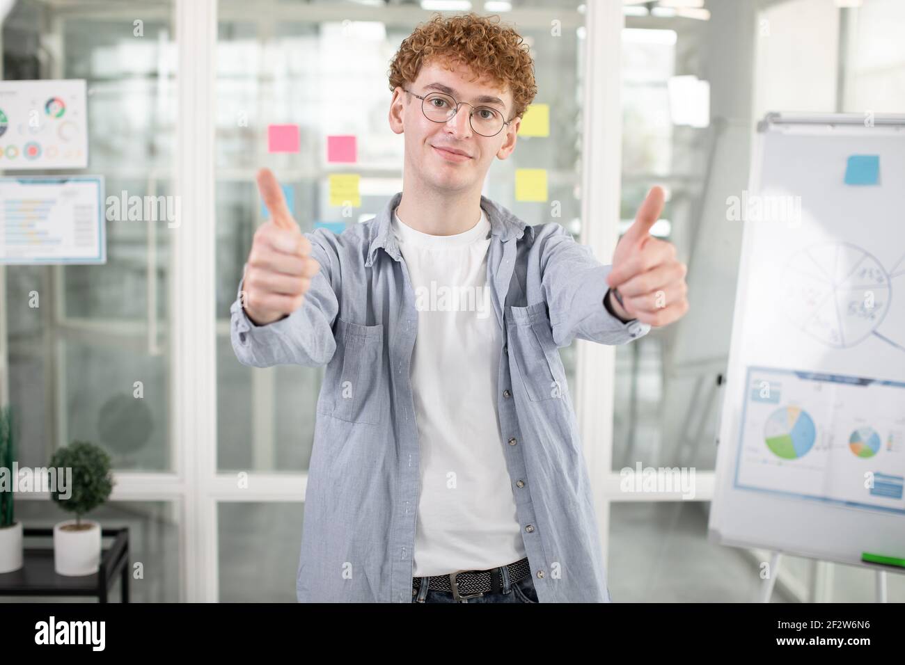 Positive young student showing thumbs up at office Stock Photo - Alamy