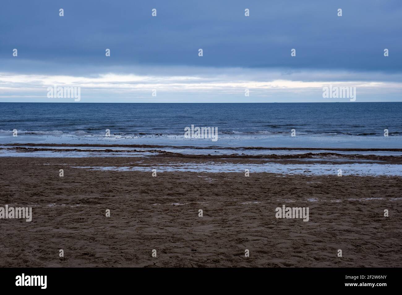 icy winter beach near the sea with frozen sand and ice blocks in the ...