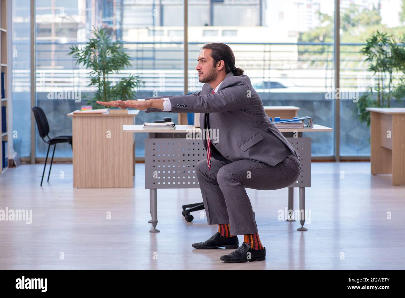 Young employee doing sport exercises at workplace Stock Photo - Alamy