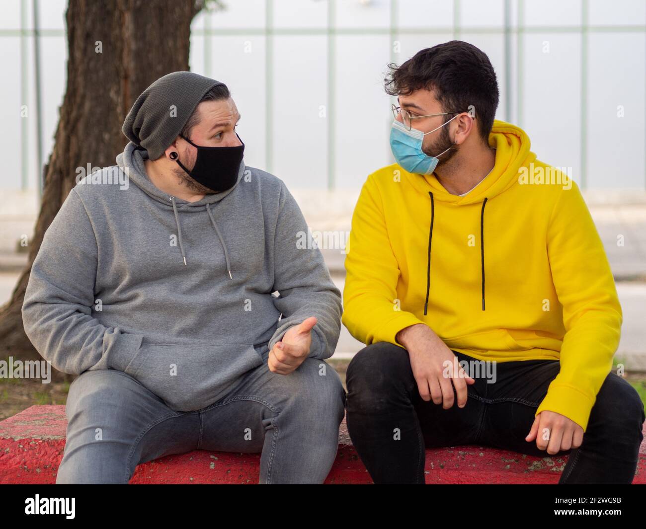 A closeup of two Spanish Caucasian men, sitting outdoors and talking ...