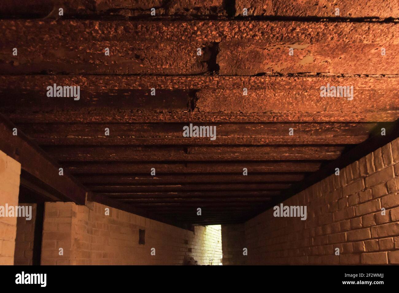 Rusty steel ceiling in a brick corridor. The corridor is very old and ...