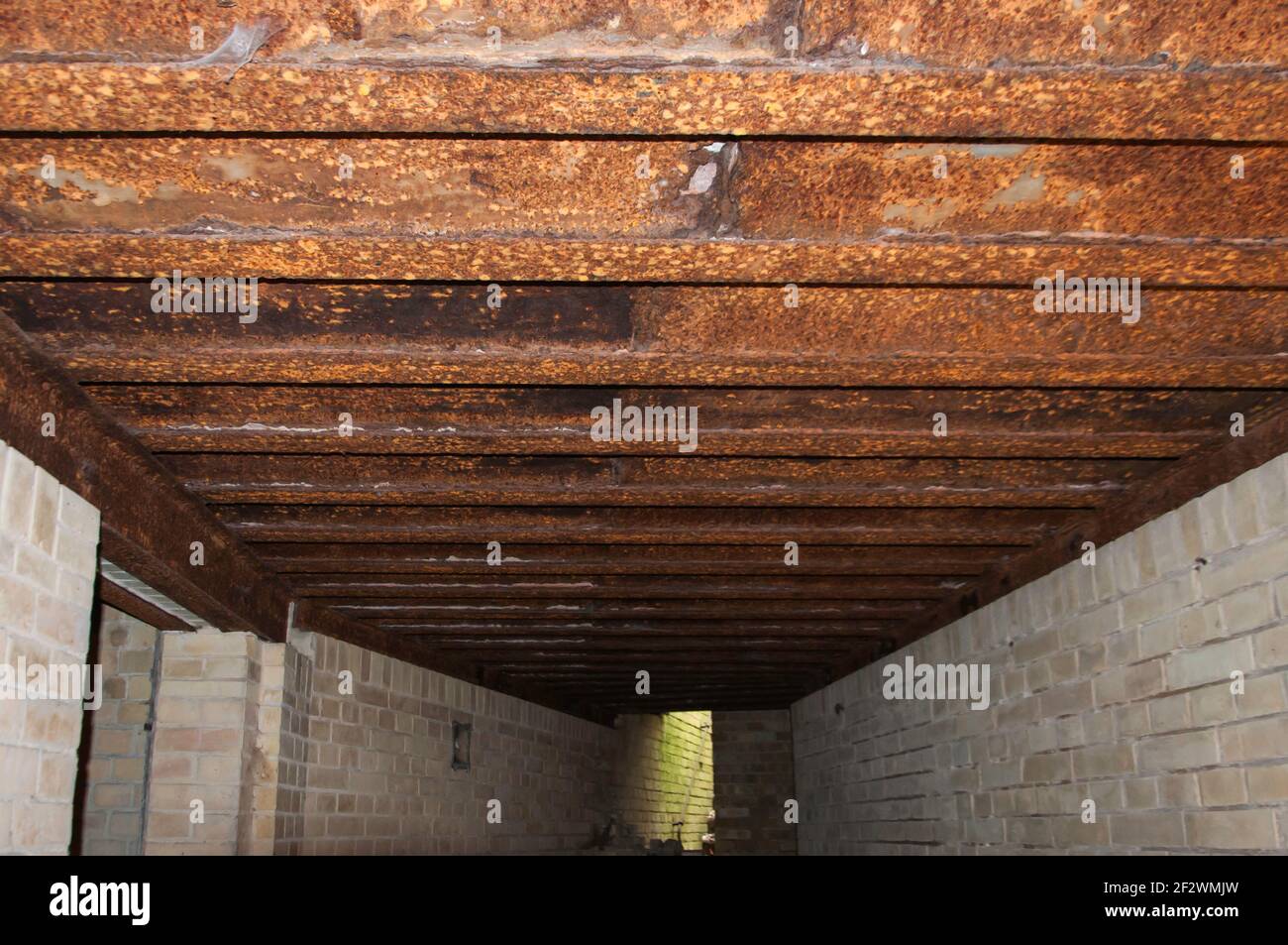 Rusty steel ceiling in a brick corridor. The corridor is very old and ...