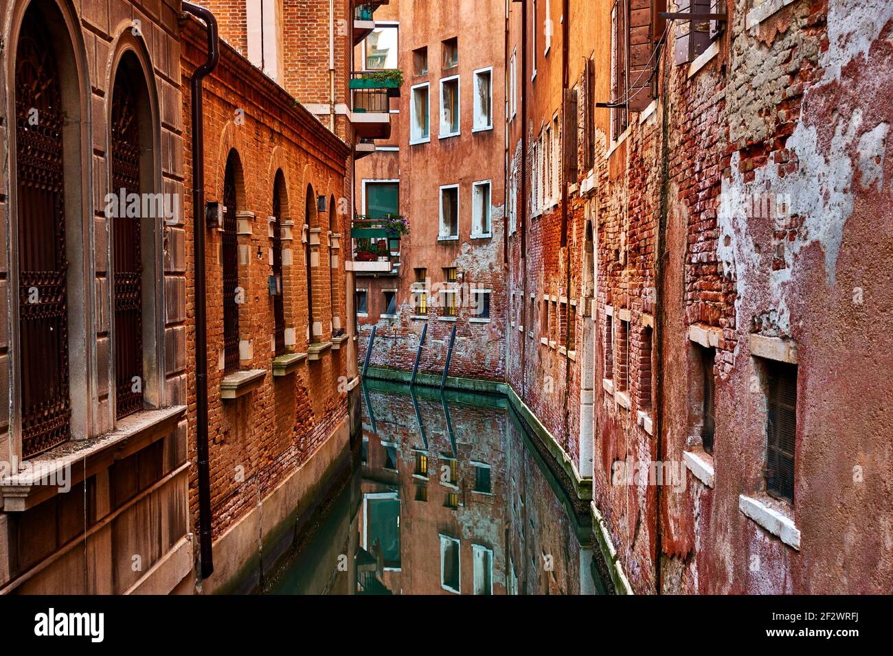 Narrow side canal between rows of old buildings in Venice, Italy ...