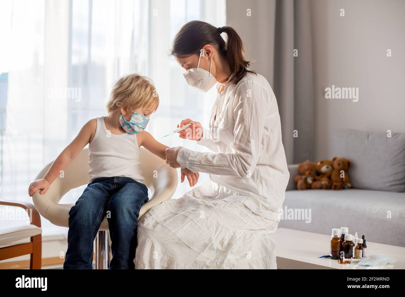 Little toddler child, blond boy, getting injection in consulting room ...