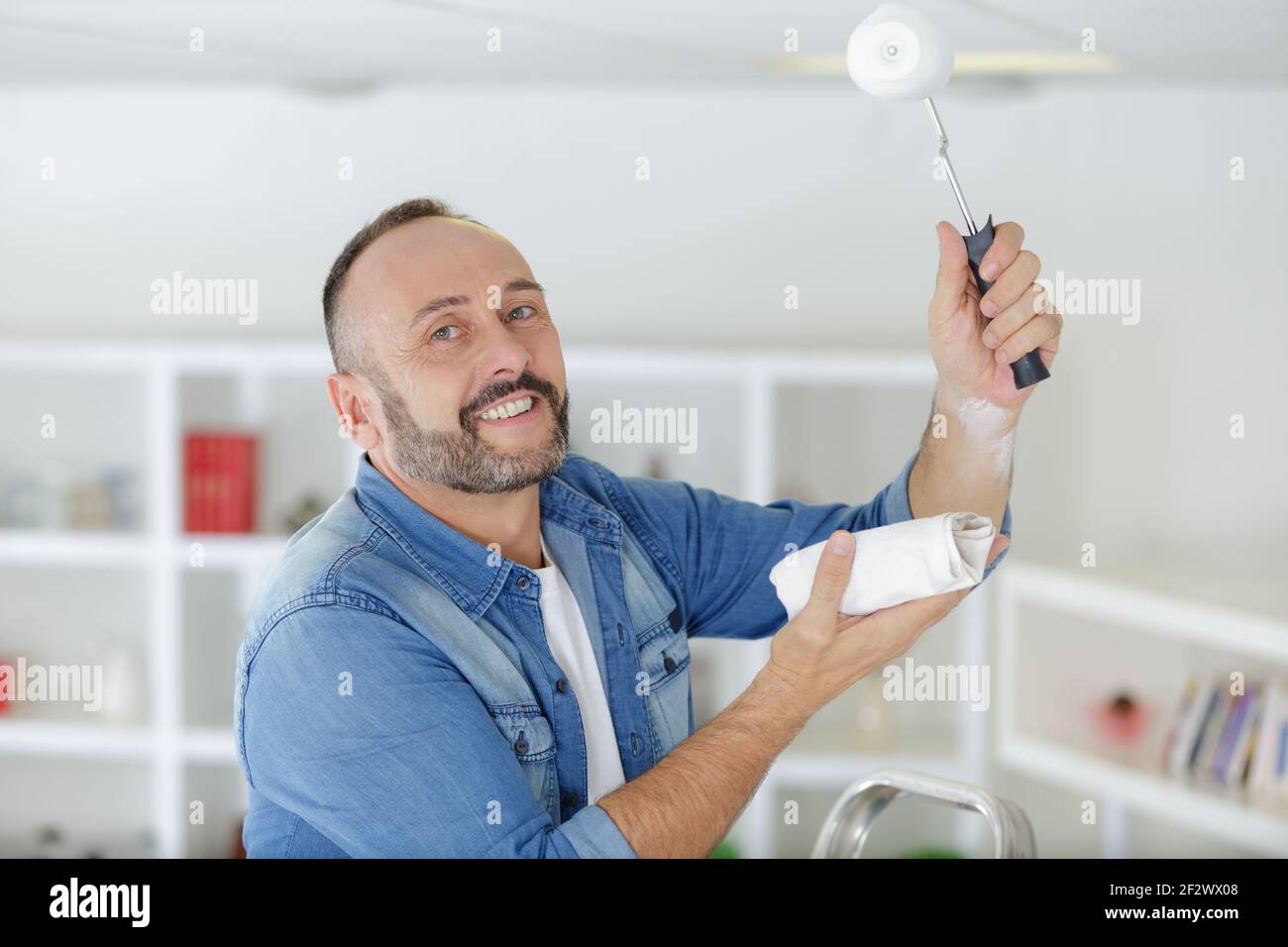 man painting ceiling in a new house Stock Photo - Alamy