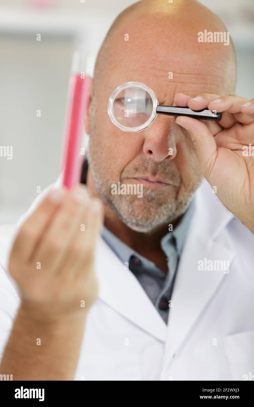 scientist looking through a magnifying glass Stock Photo - Alamy