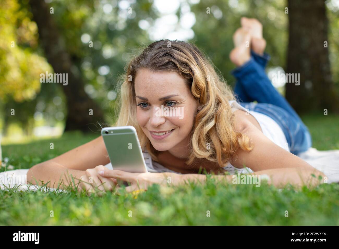young girl laying the park using mobile phone Stock Photo - Alamy