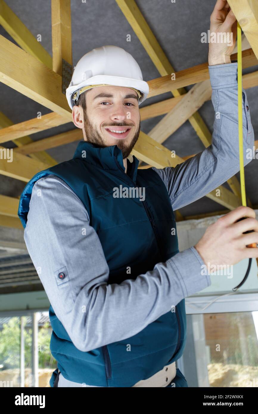 young male carpenter measuring roof beam Stock Photo - Alamy