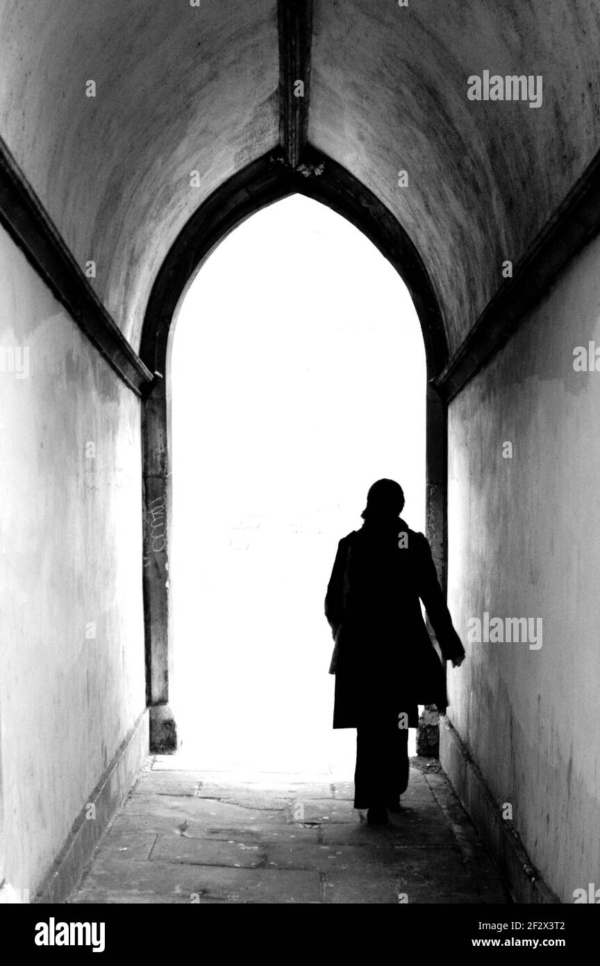 woman walking into light at end of archway Stock Photo - Alamy