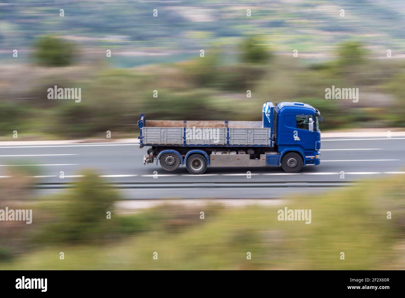Truck with three axles driving fast on the highway with the rest of the ...