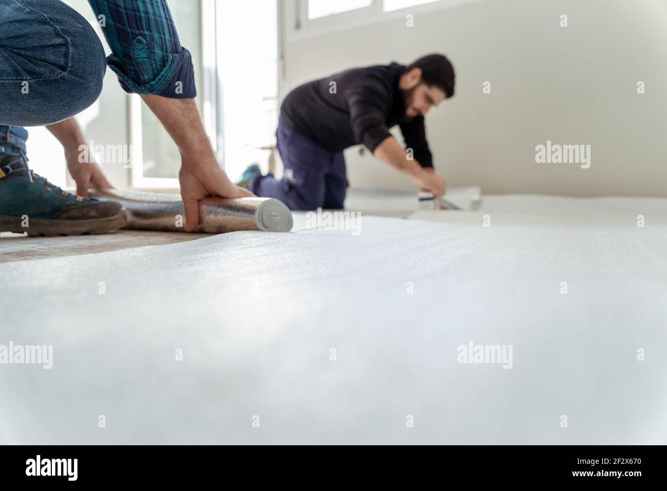 two men installing an insulating layer on the floor of the house Stock ...