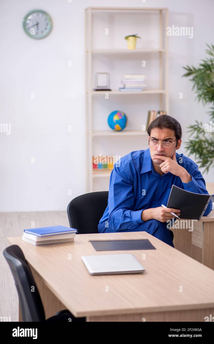 Young teacher checking notes in the classroom Stock Photo - Alamy