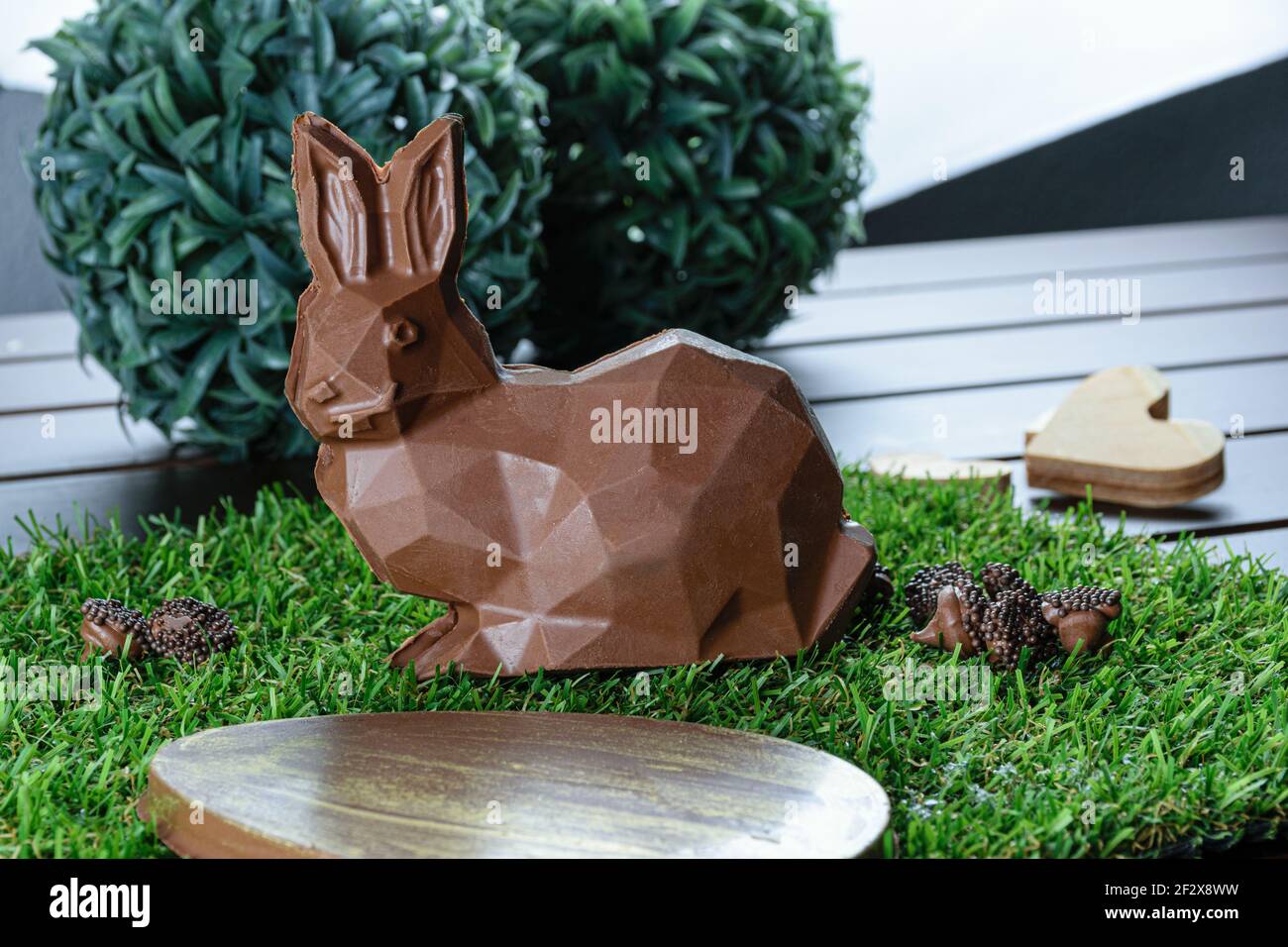 Rabbit-shaped chocolate on a fake lawn. Next to chocolate drops with ...
