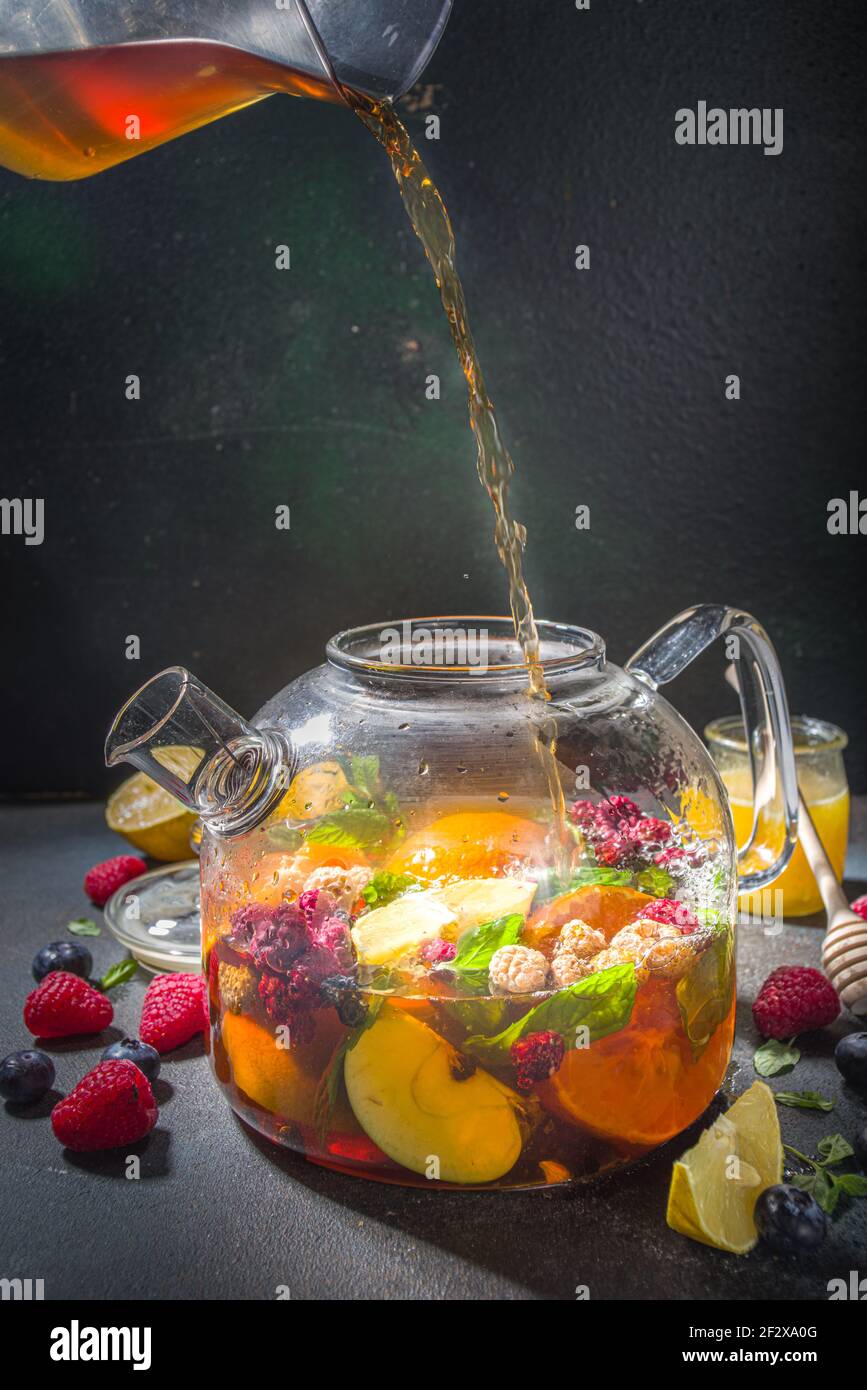 Fruit and berry tea in teapot. Hot drink with lemon, mint, blueberry ...
