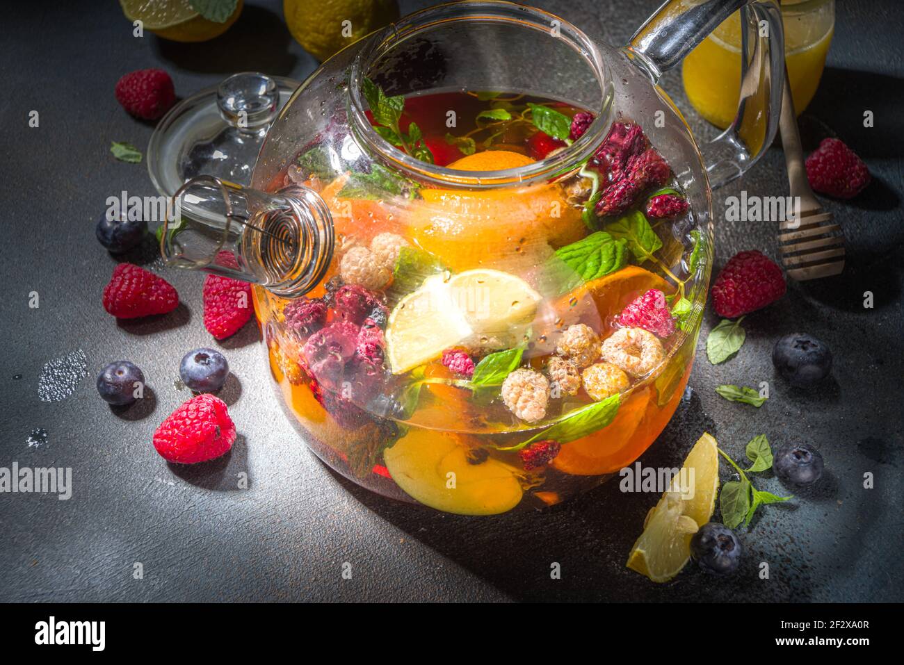 Fruit and berry tea in teapot. Hot drink with lemon, mint, blueberry ...