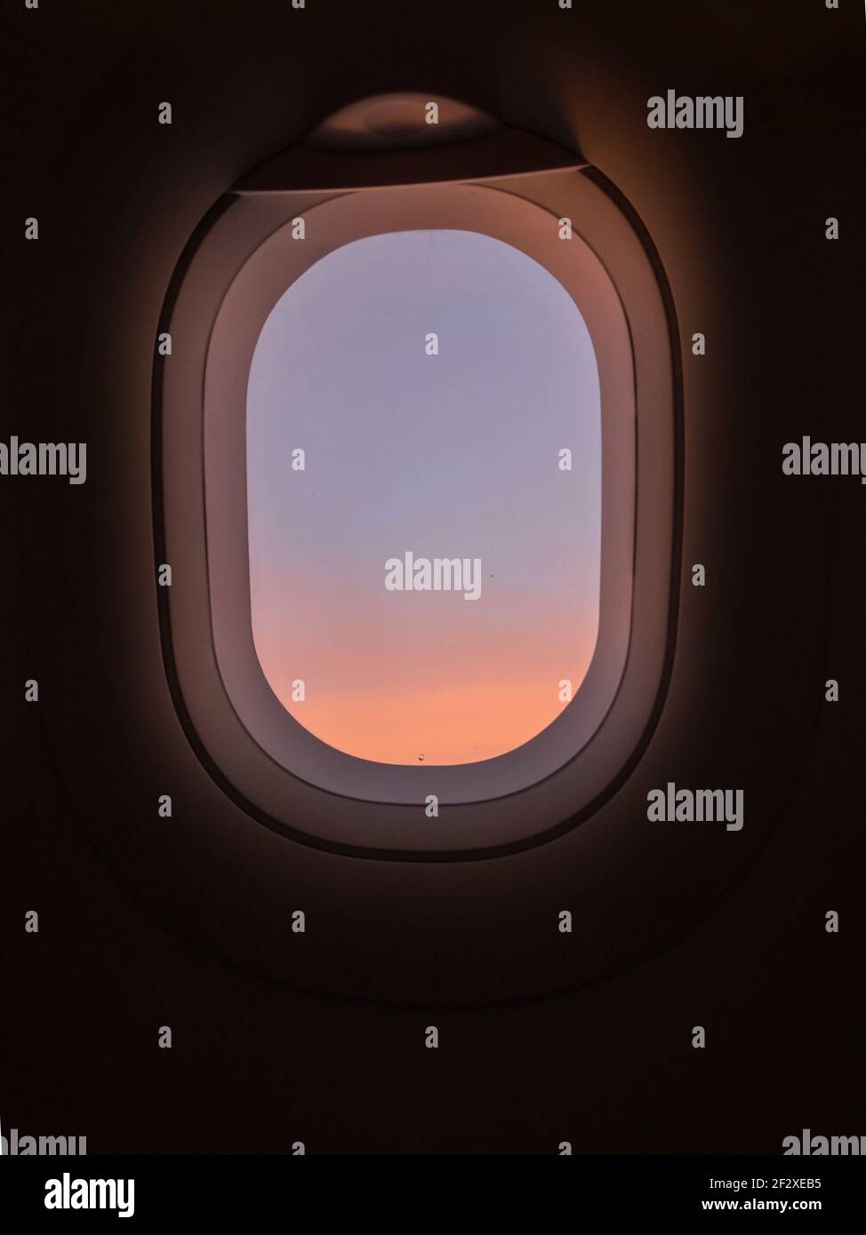 Typical airplane window view with pastel sky sunset and dark background ...