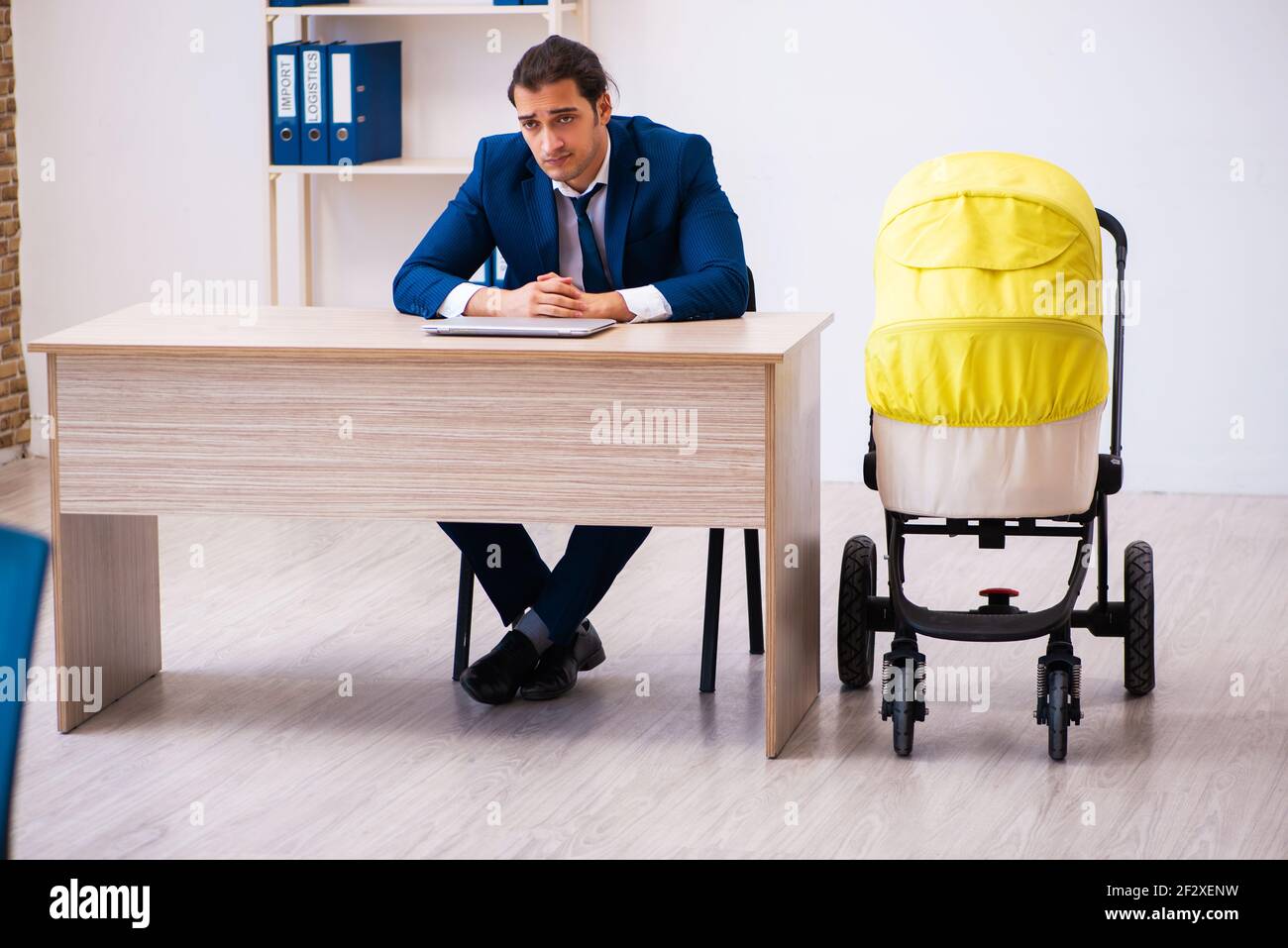 Young employee looking after kid at workplace Stock Photo - Alamy