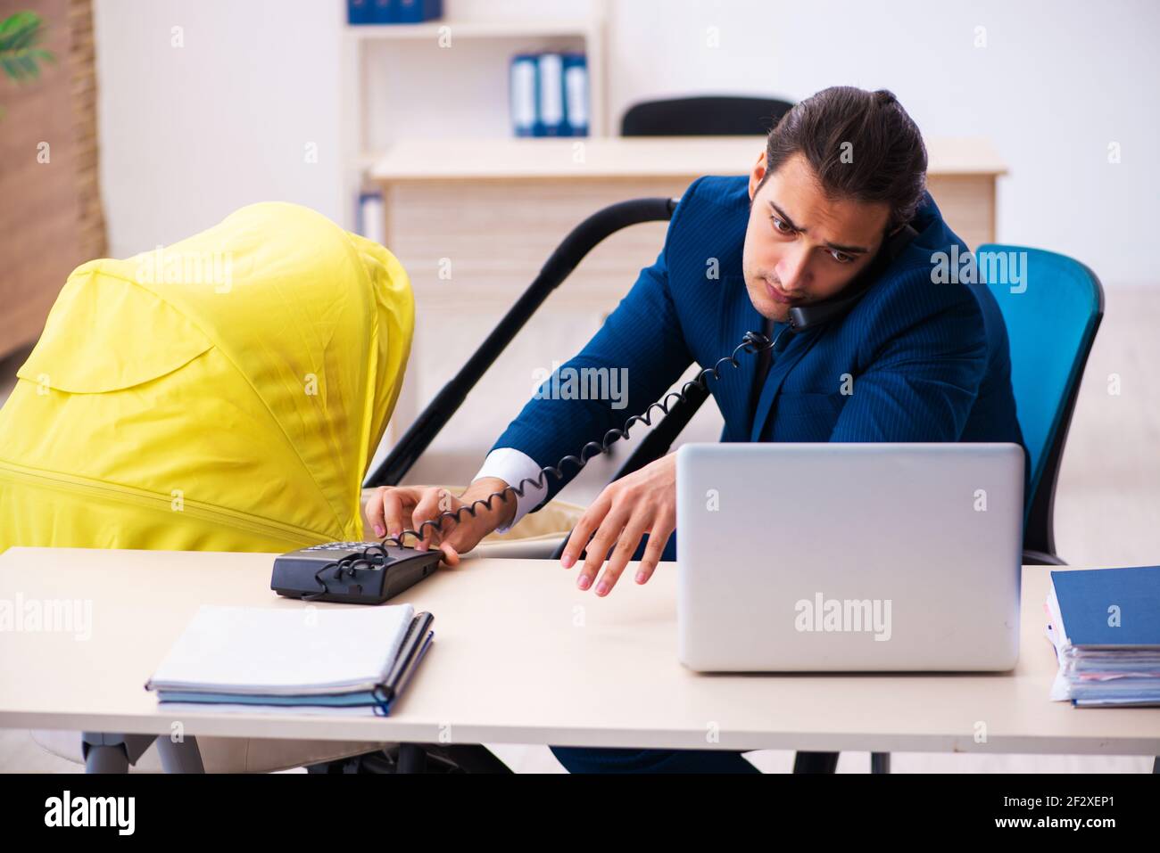 Young employee looking after kid at workplace Stock Photo - Alamy