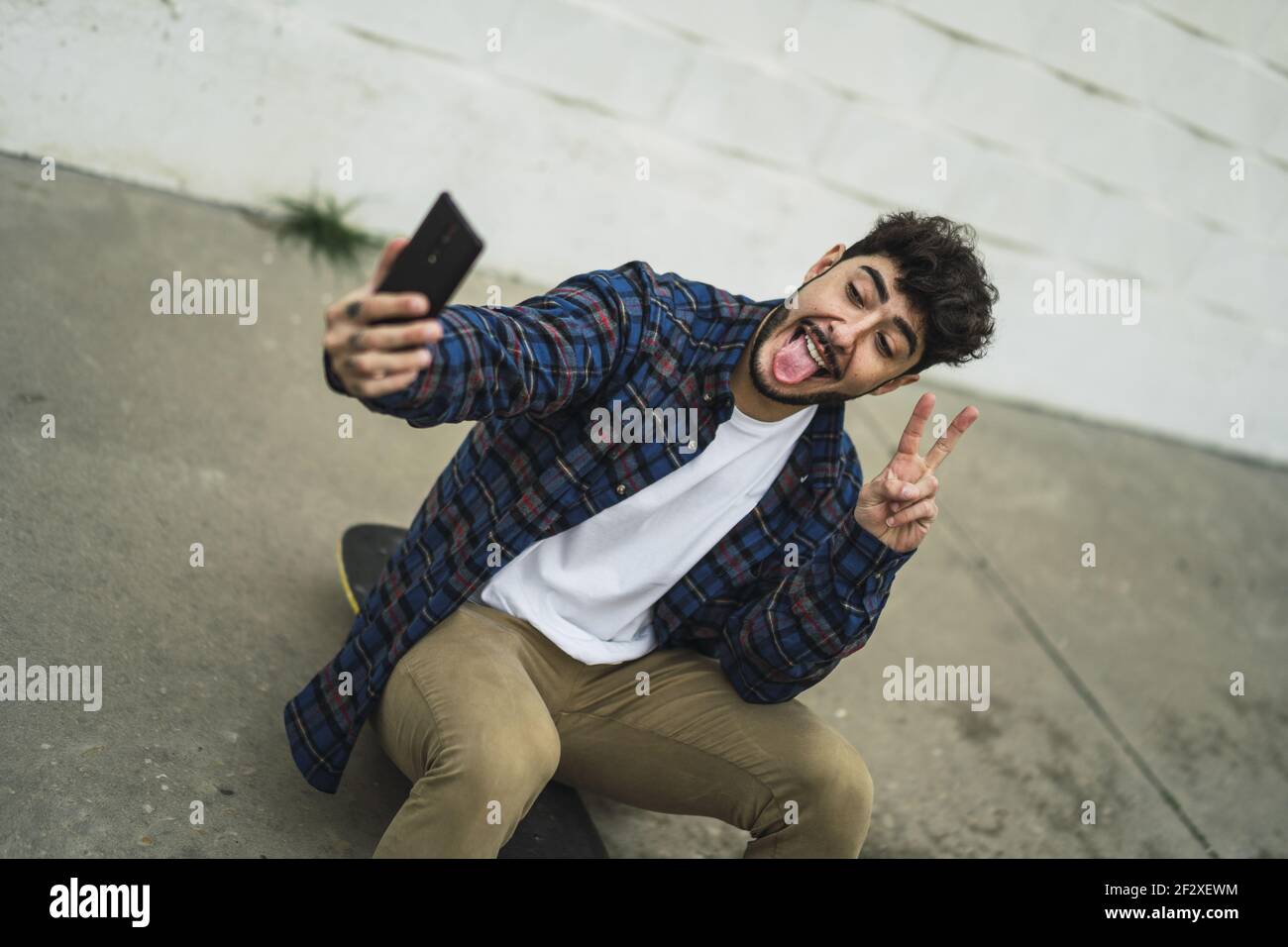 A cool Spanish male taking a selfie and showing the V sign Stock Photo ...