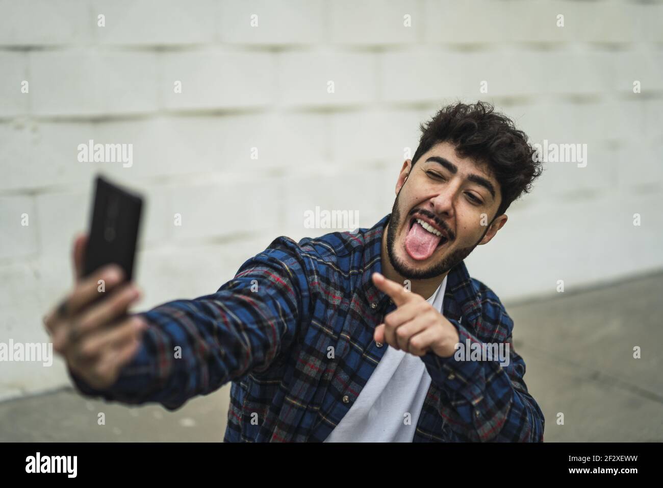 A cool Spanish male taking a selfie and pointing on the camera Stock ...