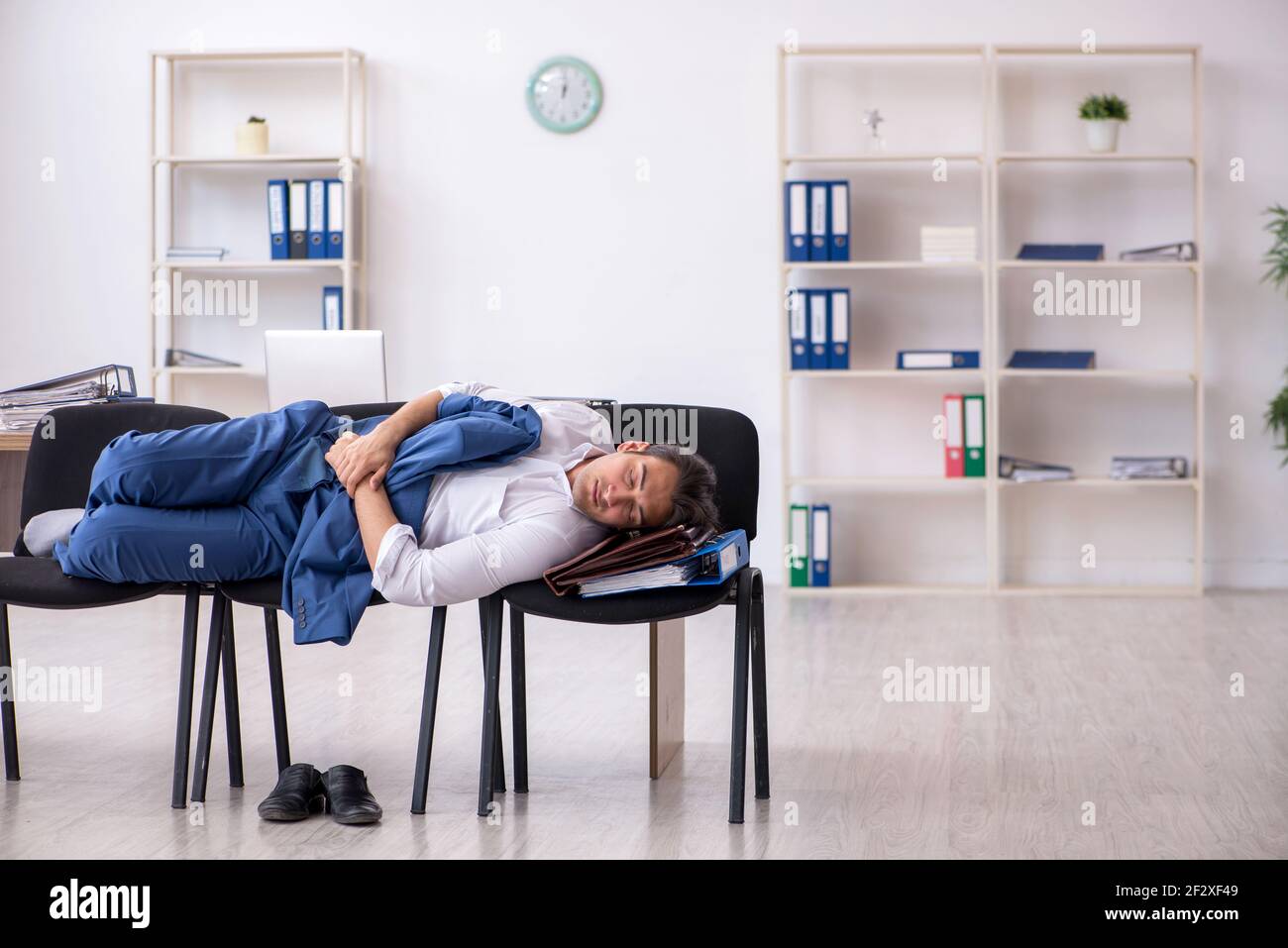 Young employee sleeping in the office on chairs Stock Photo - Alamy