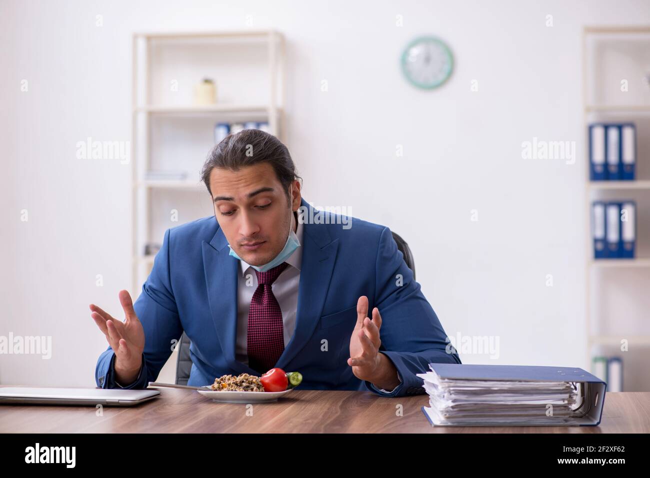 Hungry employee eating buckwheat during break Stock Photo - Alamy