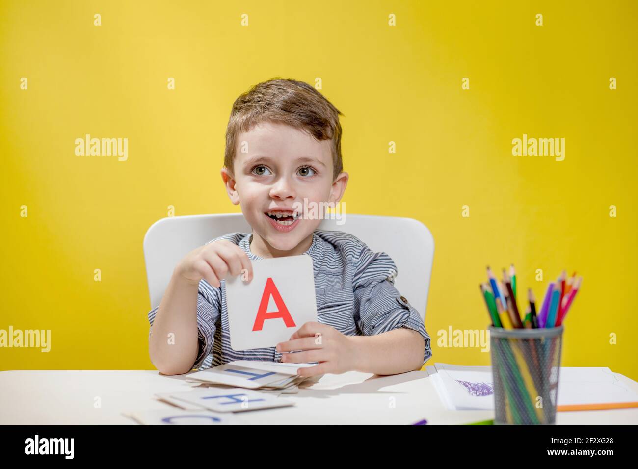 Happy smiling little preschool boy shows letters at home making ...