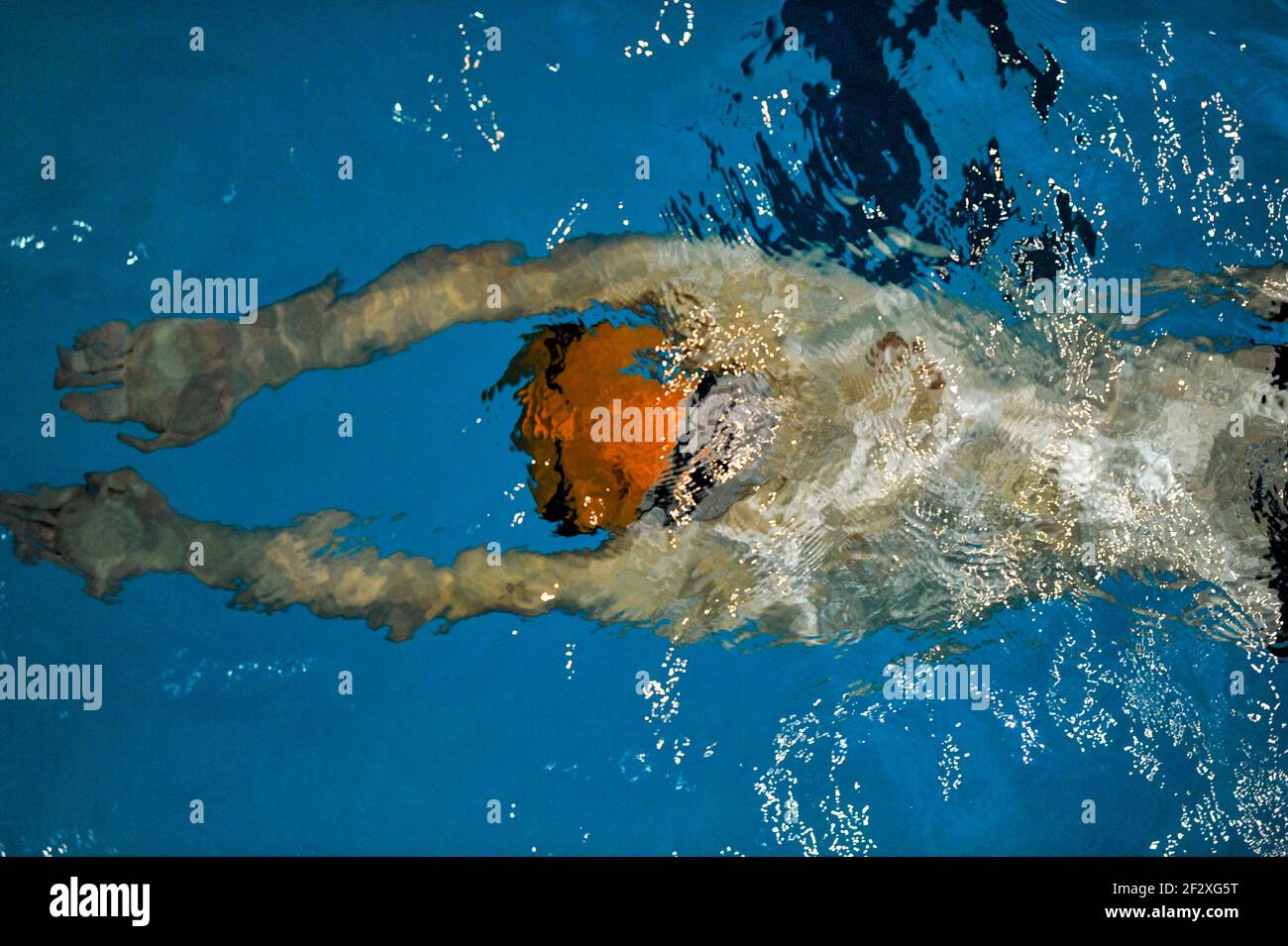 A male backstroke swimmer swims underwater at the turn in an Olympic ...