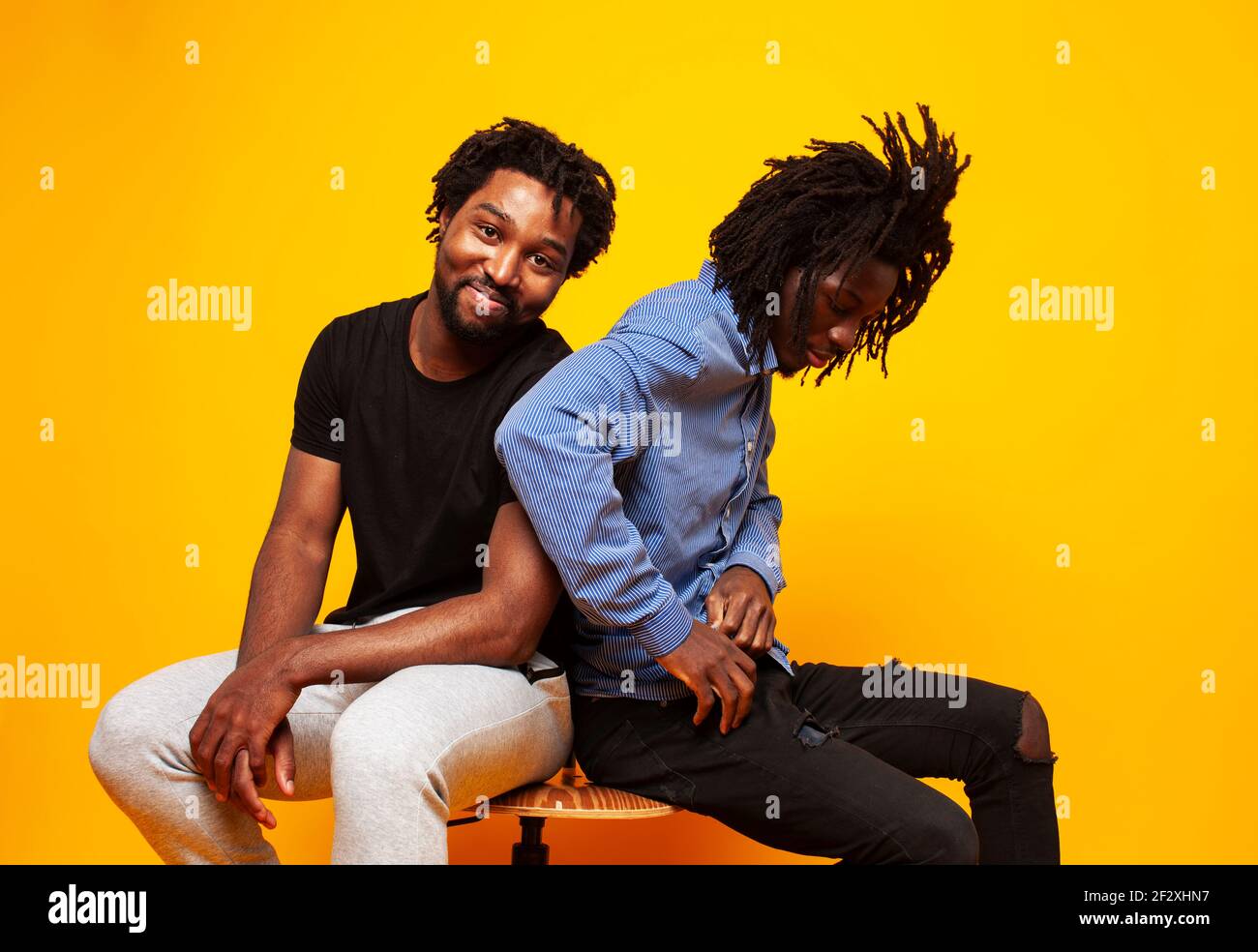 two african american guys posing cheerful together on yellow background ...