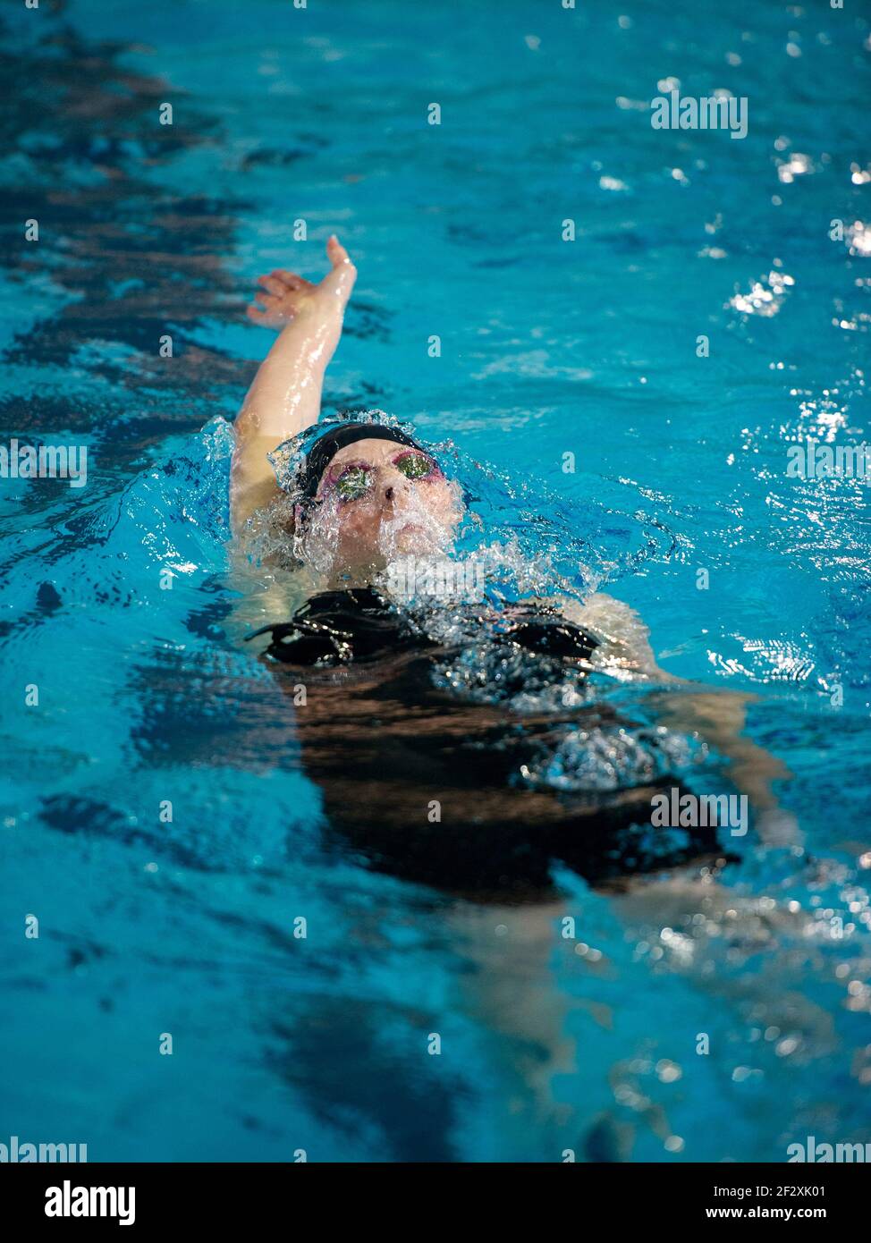A female backstroke swimmer comes to the surface in a race in an ...