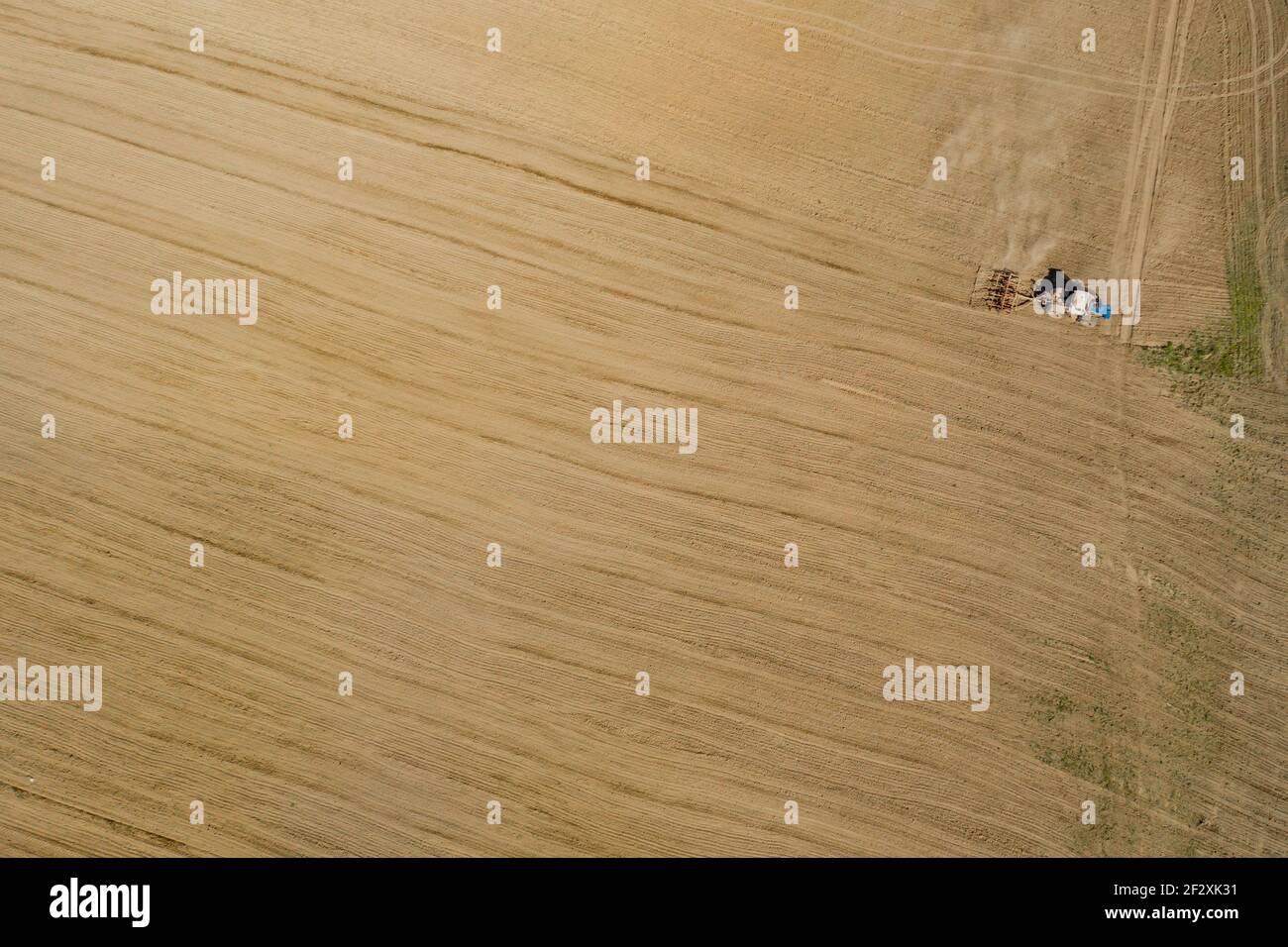 Aerial view large tractor cultivating a dry field. Top down aerial view ...