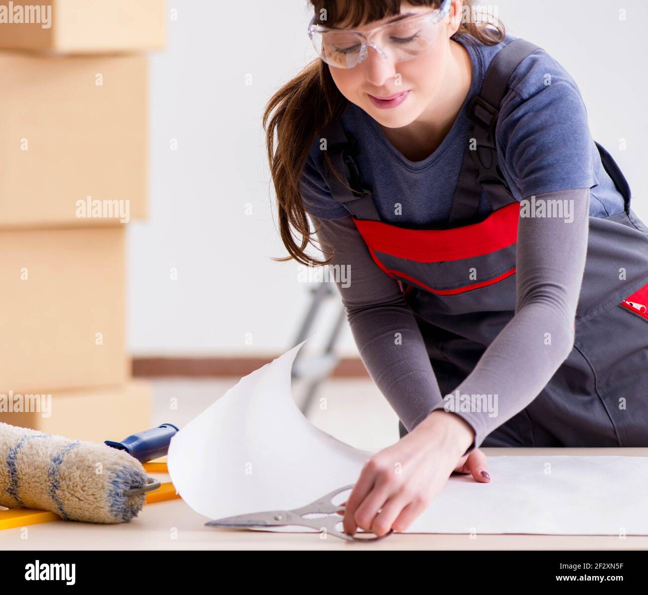 Woman applying wallpaper glue on a wallpaper with a brush hi-res stock ...