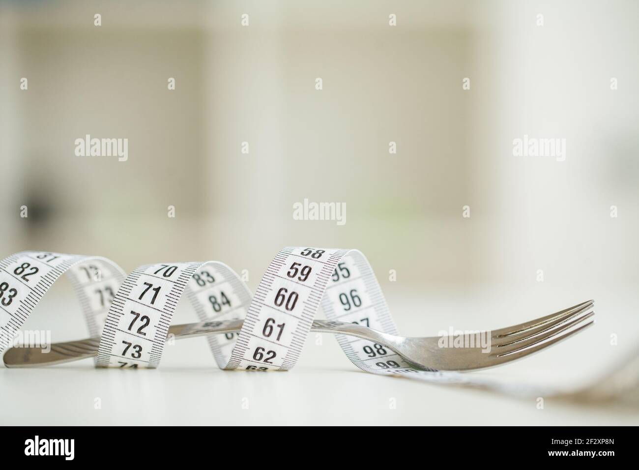 Measuring tape and a fork on white background Stock Photo - Alamy