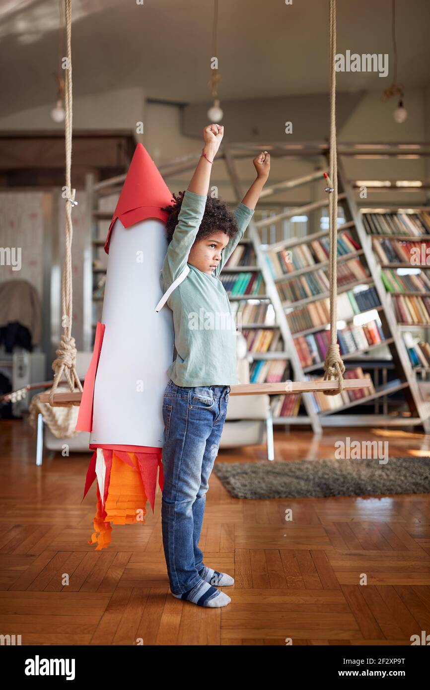 A little boy with a rocket toy on his back is imagining flying to the ...