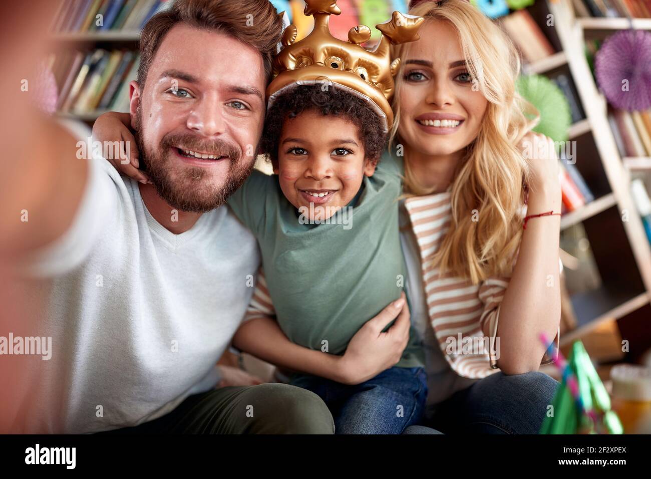 Happy couple posing for a photo with their adopted son at kids birthday ...