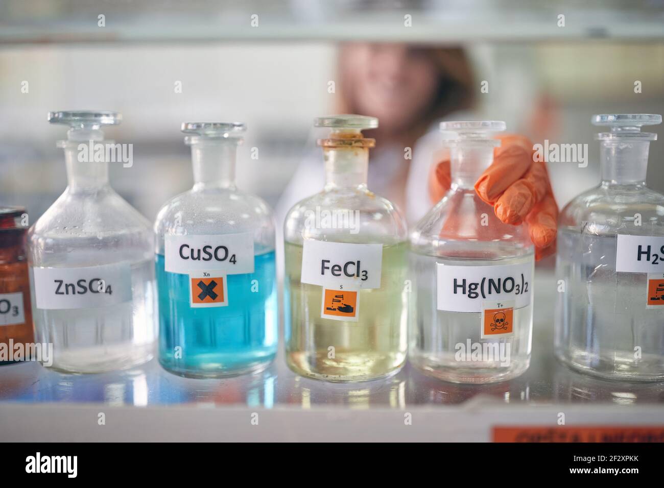 An institution employee handling bottles with chemicals in a sterile ...