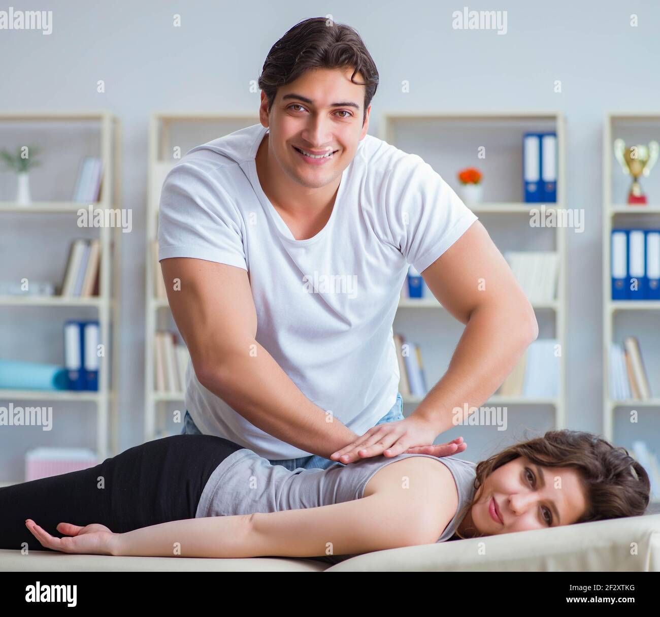 The young doctor chiropractor massaging female patient woman Stock ...