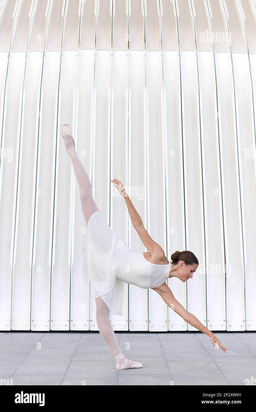 Side view of young female ballet dancer in pointe shoes with raised leg ...