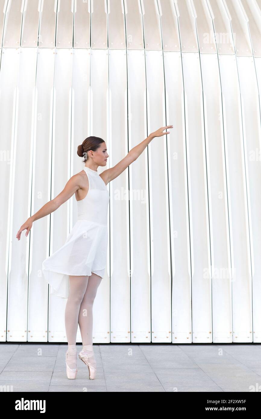 Young female ballet dancer in tiptoe in pointe shoes with raised leg ...